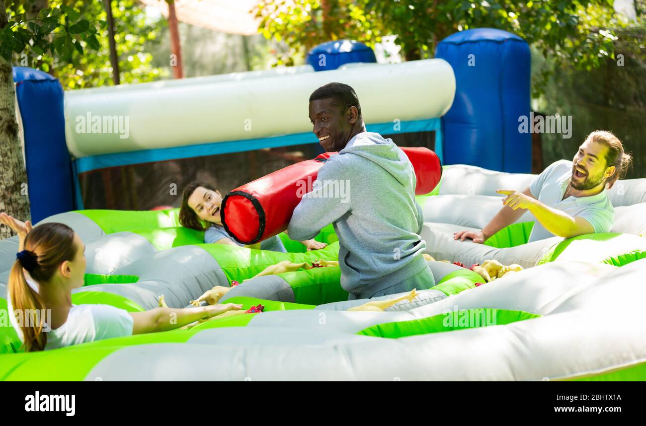 Funny friends playing on an inflatable trampoline in an amusement park ...