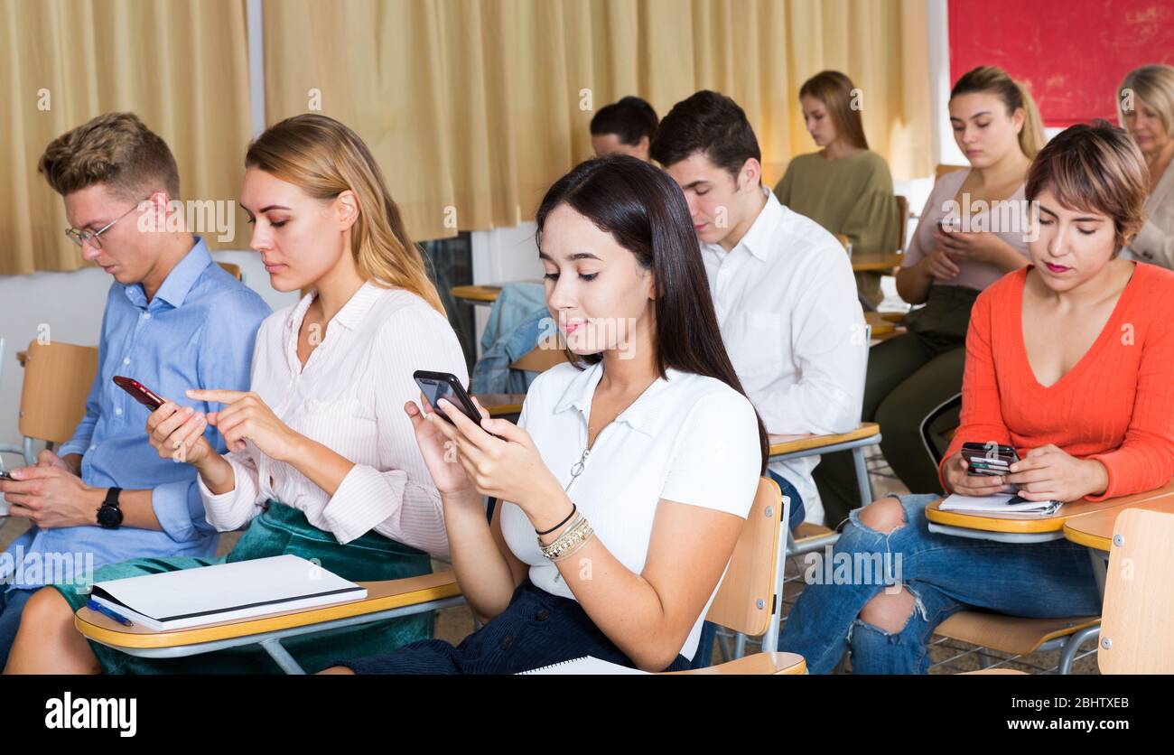 Group of modern people sitting with mobile phones on lecture in ...