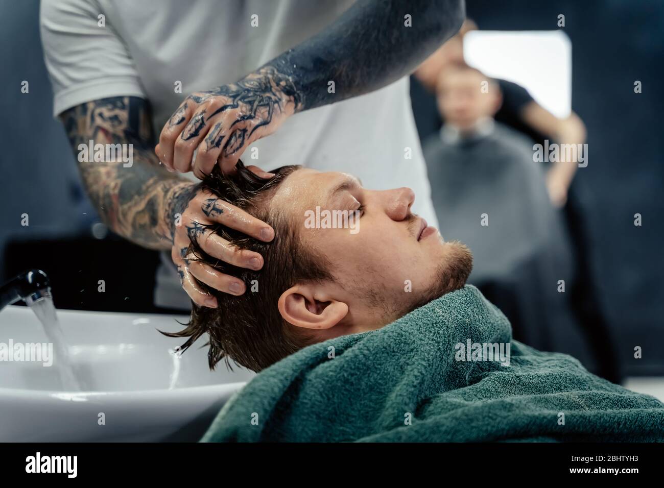 Attractive male is getting a modern haircut in barber shop. Top view of ...