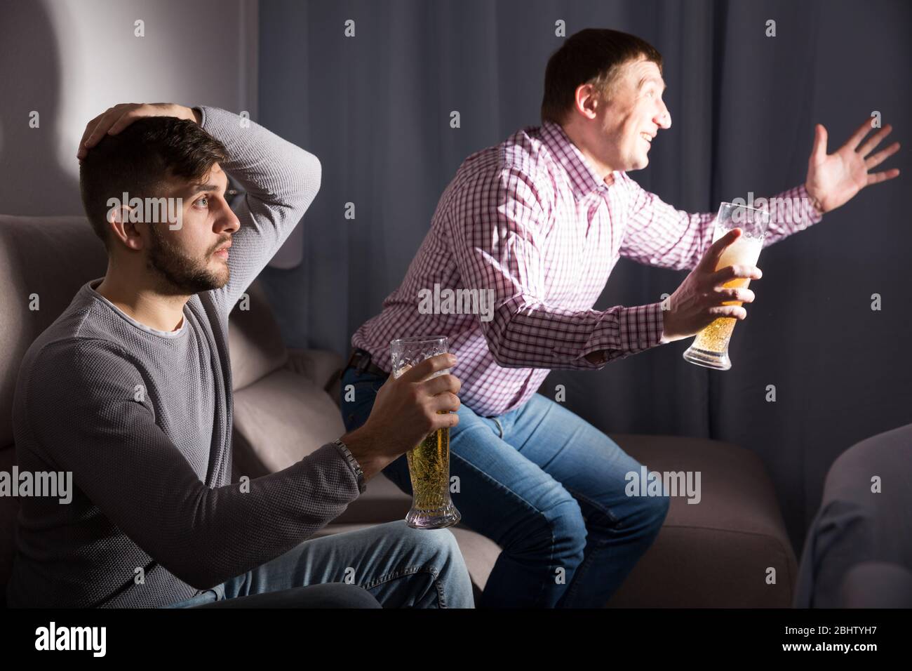 Two friends watching matchup on tv together, but supporting different ...