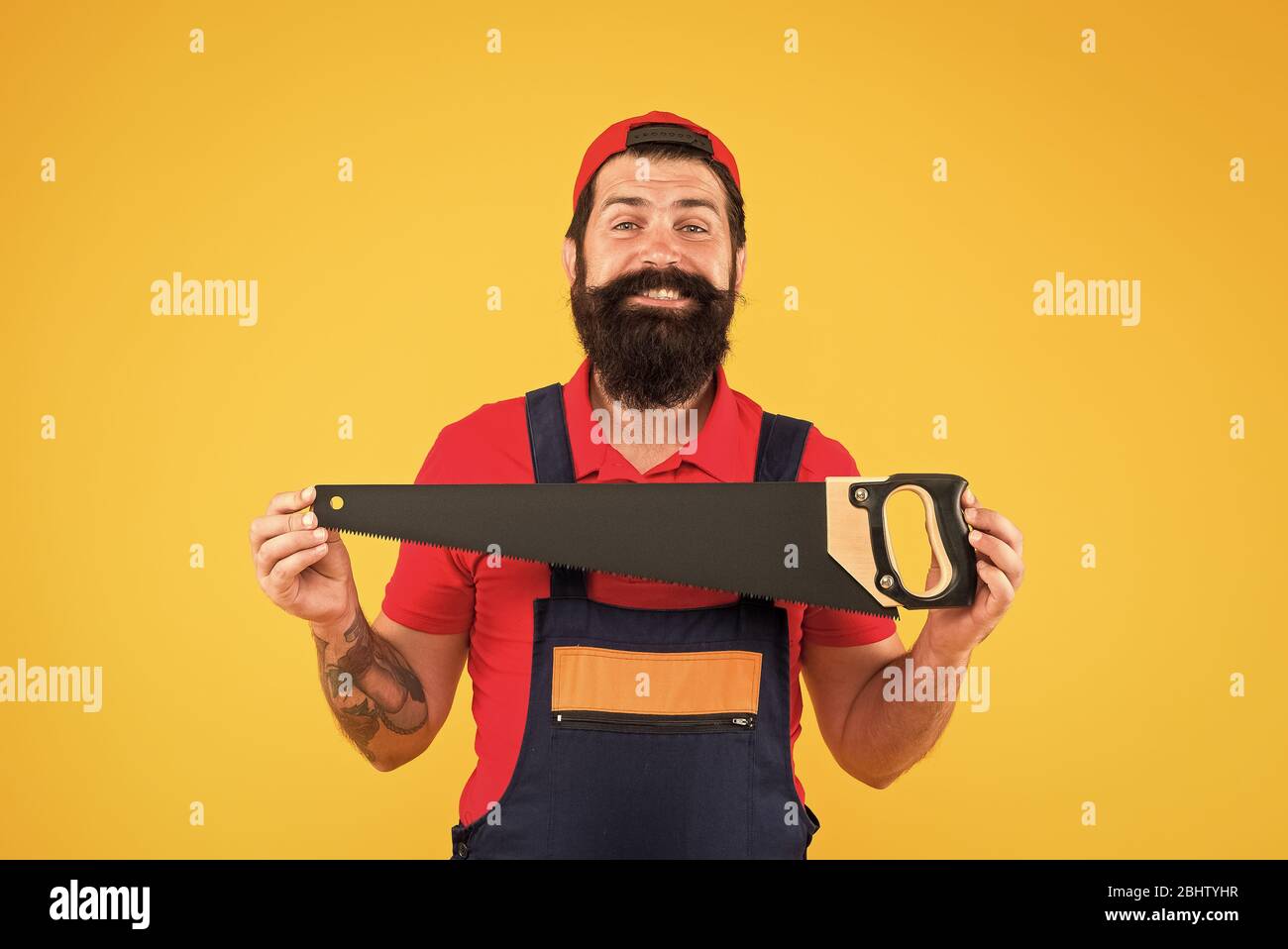 Handsome smiling man happy with saw yellow background. Gardener ...