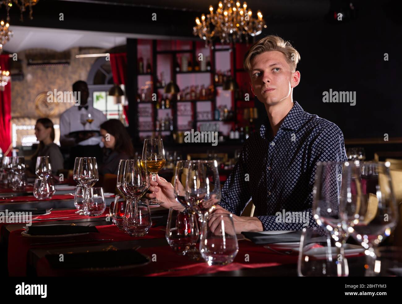 Portrait of single handsome young man drinking wine in luxury ...