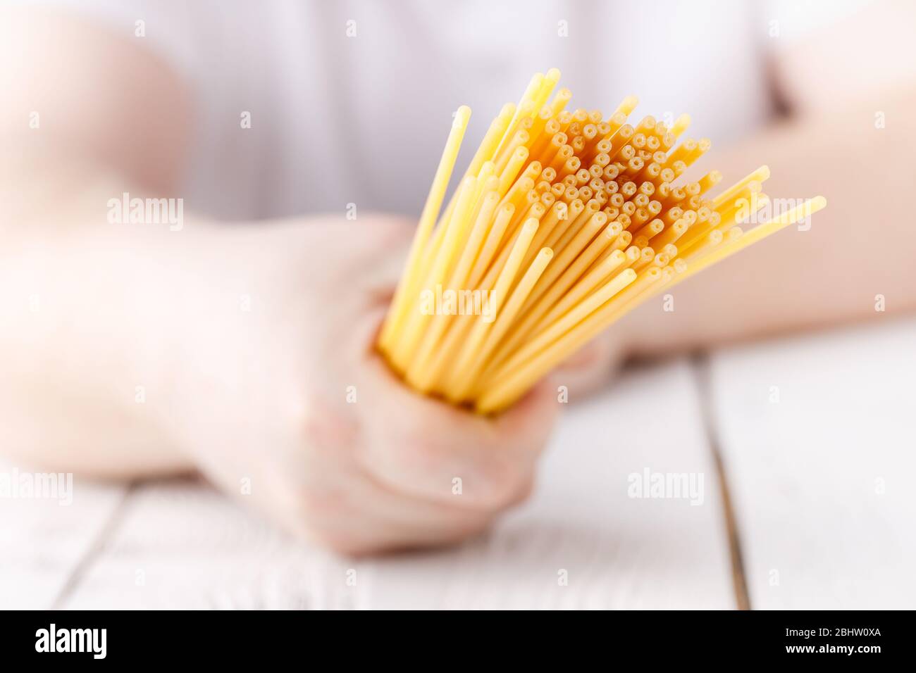 Hand full of raw dry spaghetti, close up view Stock Photo - Alamy