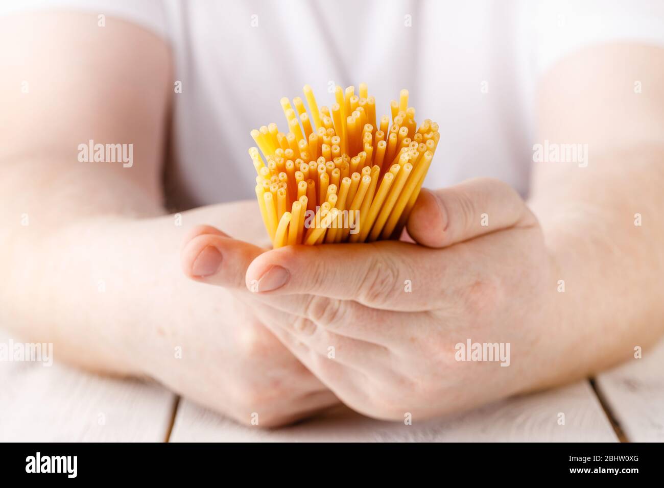 Hand full of raw dry spaghetti, close up view Stock Photo - Alamy