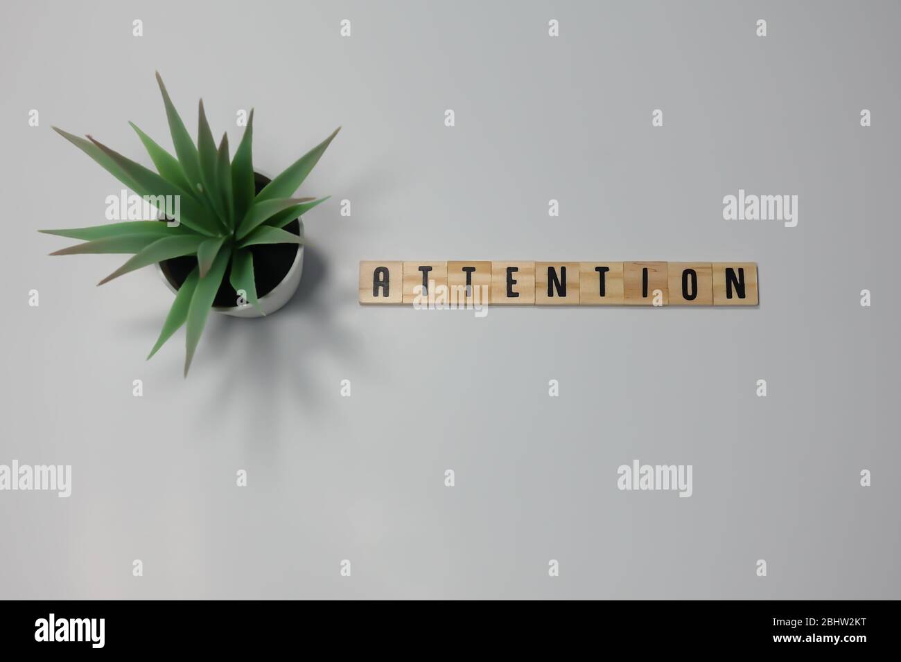 The word Attention written in wooden letter tiles on a white background ...