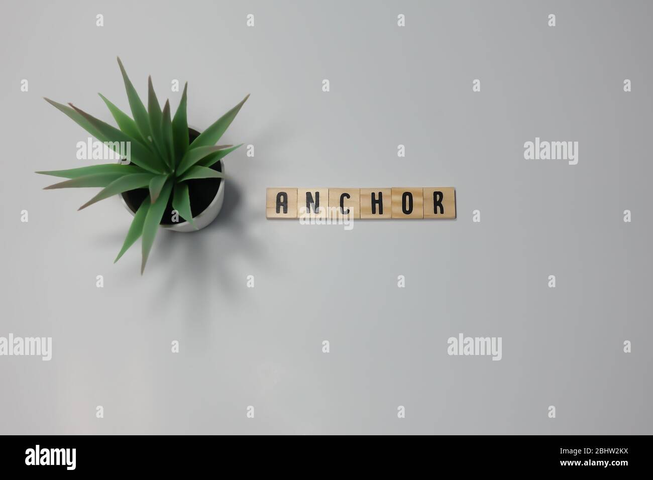 The word Anchor written in wooden letter tiles on a white background ...