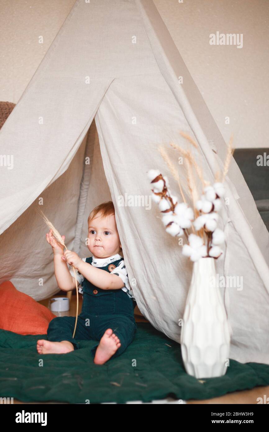 Sweet 1 year old little baby boy playing in a teepee game tent in a ...