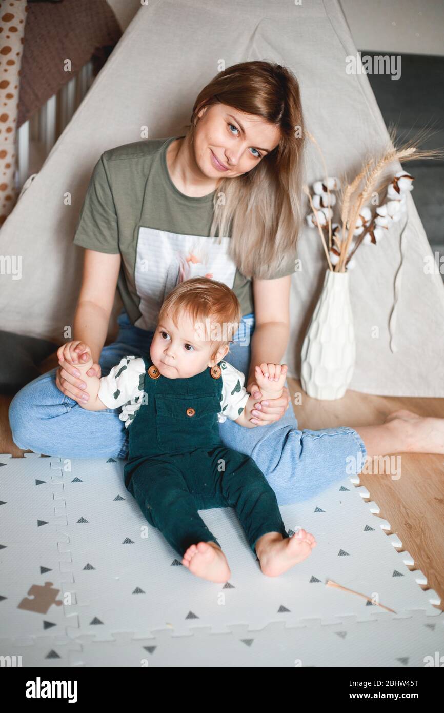Beautiful mother and baby boy dressed in green overalls sitting on the ...
