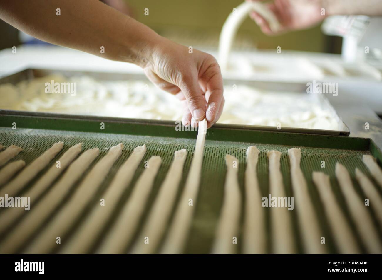 Stretching organic breadsticks in Italy before baking Stock Photo - Alamy