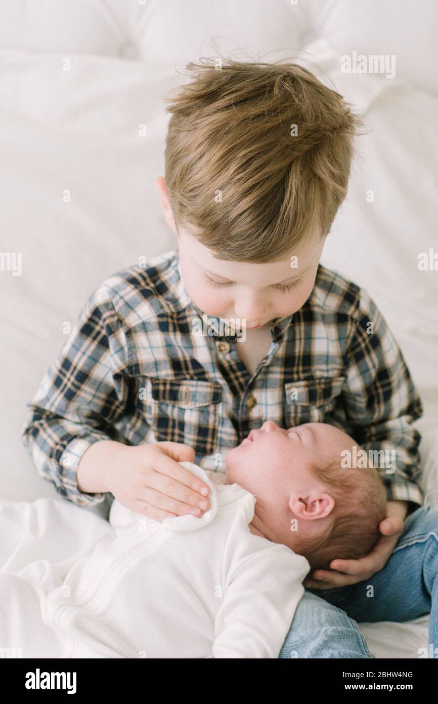 Big brother hold baby sister for first time on bed Stock Photo - Alamy