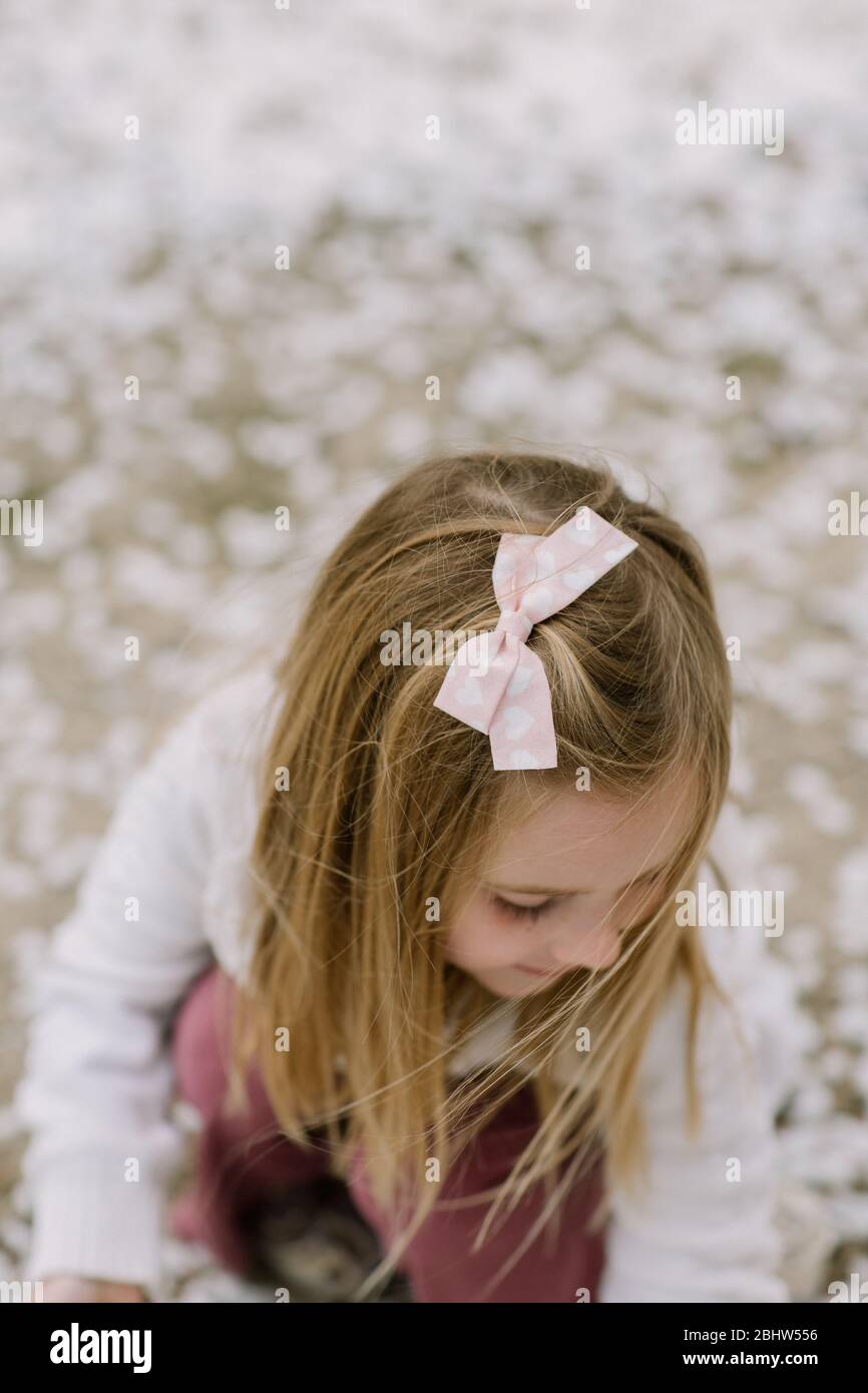 Preschool girl looking down at ground outside Stock Photo - Alamy