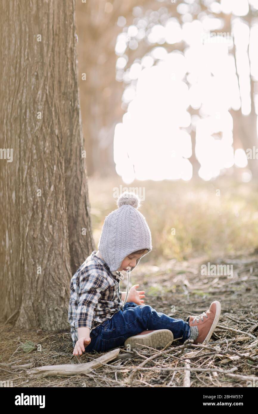 Boy sitting against tree hi-res stock photography and images - Alamy