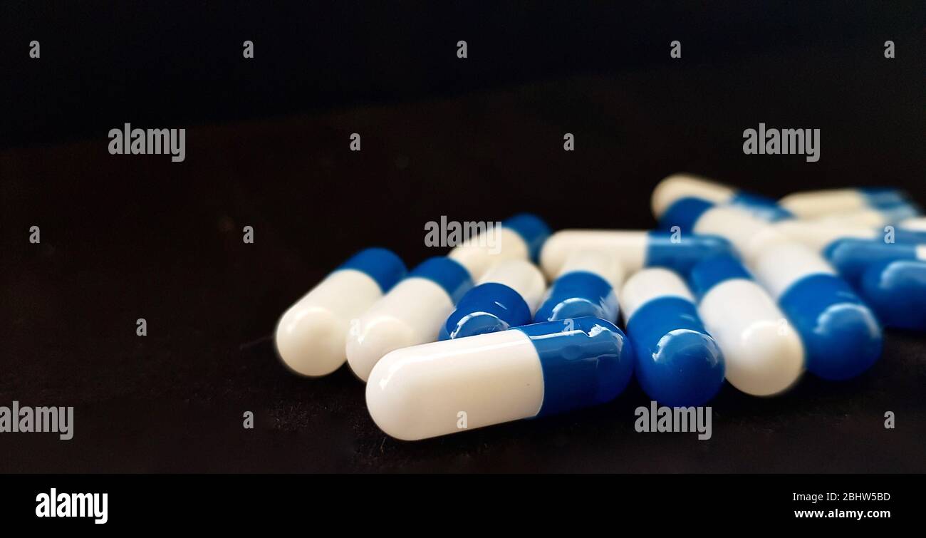 Blue and white pharmacy capsules on black background Stock Photo - Alamy