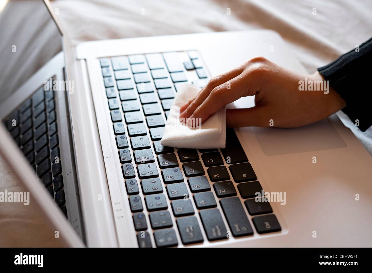 Hand disinfecting the laptop keyboard with a wipe. Disinfectant concept ...