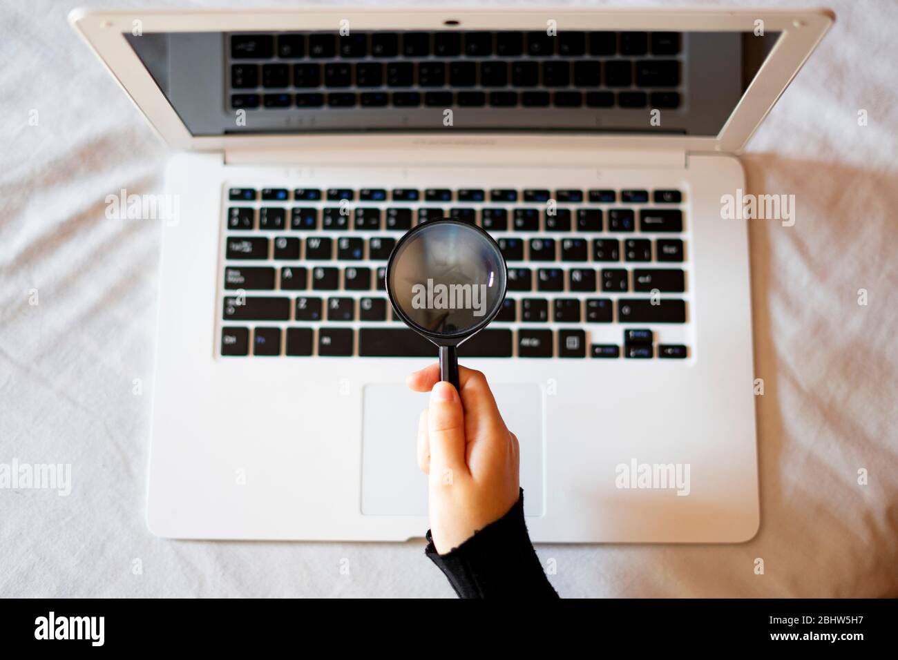 Hand with magnifying glass on top of a computer. Internet search ...