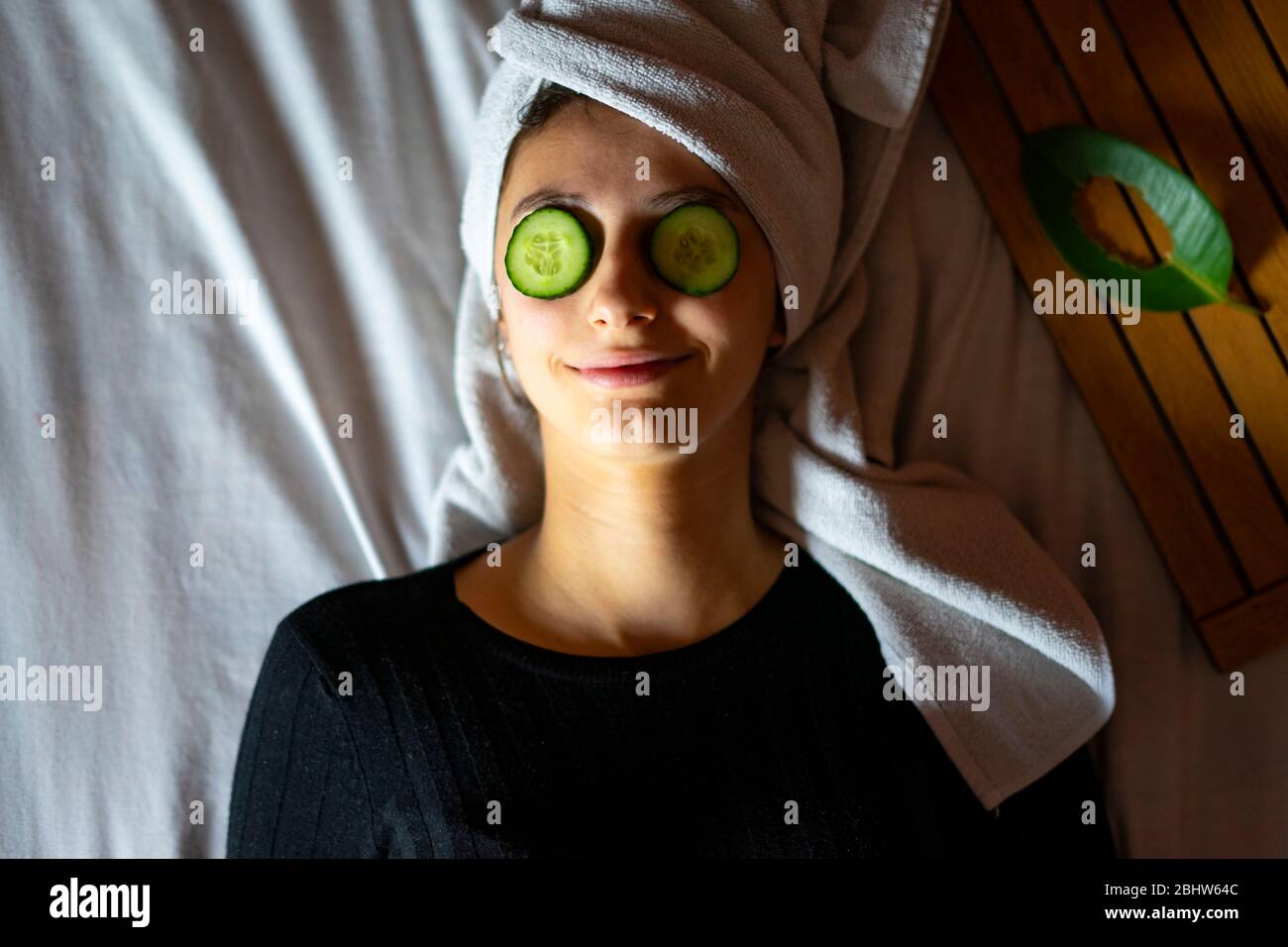 Woman lying in bed with two cucumber slices on her eyes. Home spa concept Stock Photo - Alamy