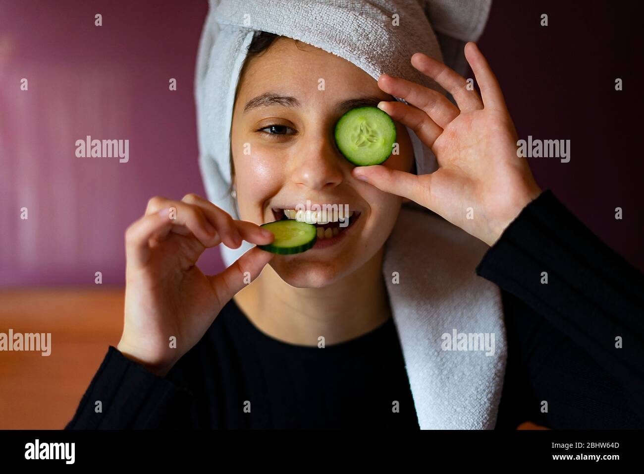 Woman with cucumber slice in her eye and eating it. Concept of cucumber ...