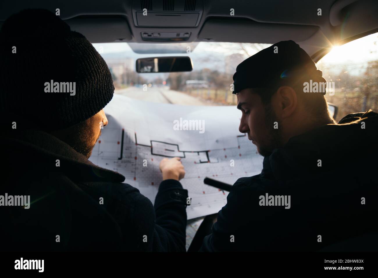 Two robbers planning and pointing on the blueprint(map) their objective ...