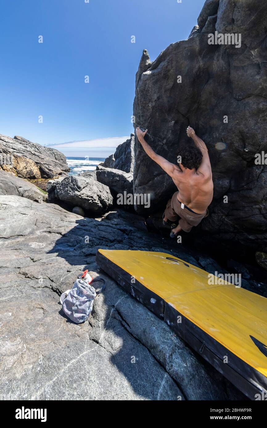 Male rock climber practicing bouldering without rope on a boulder area ...