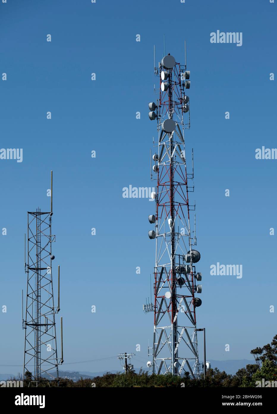 Two communication towers on a hill above the city Stock Photo - Alamy