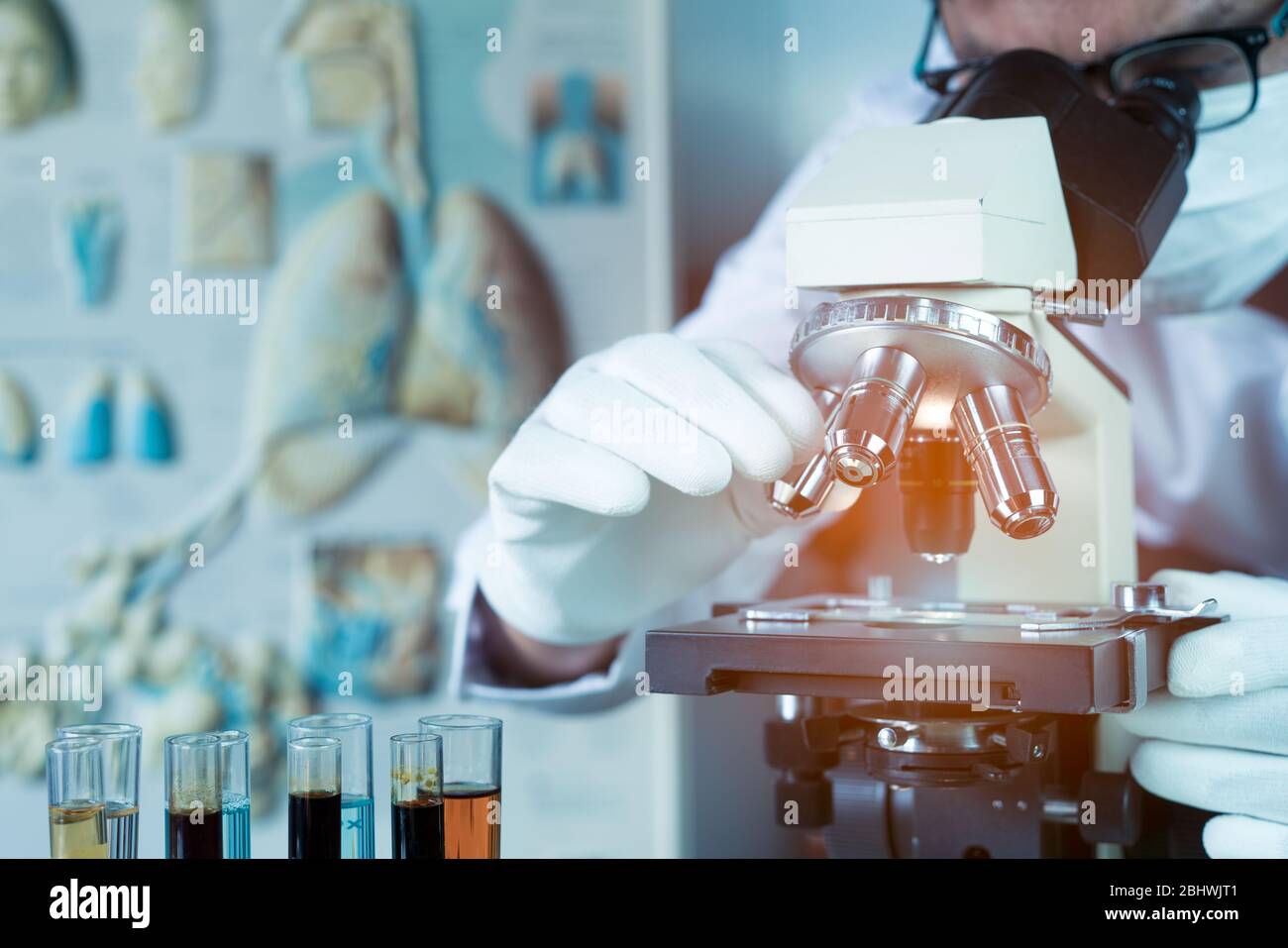 Doctor or scientist wear medical face mask and looking in microscope ...