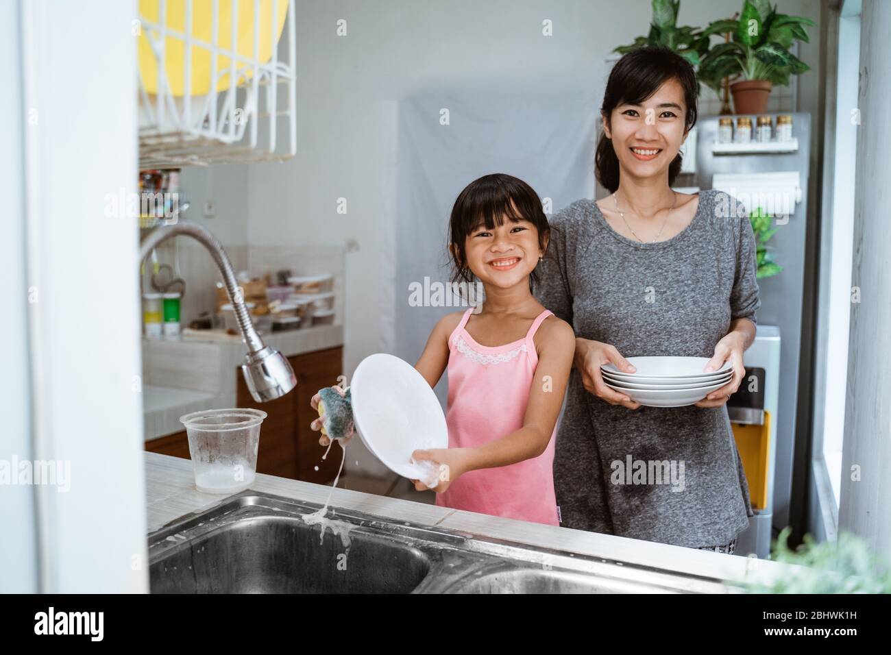 Helping hand. Cute little Girl Help Her Mother In Washing Dishes At ...
