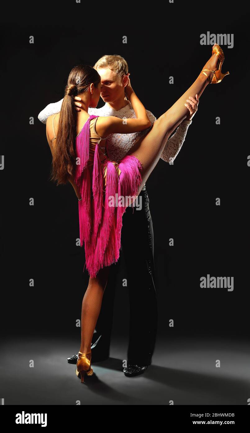 Beautiful couple of professional artists dancing on black background ...