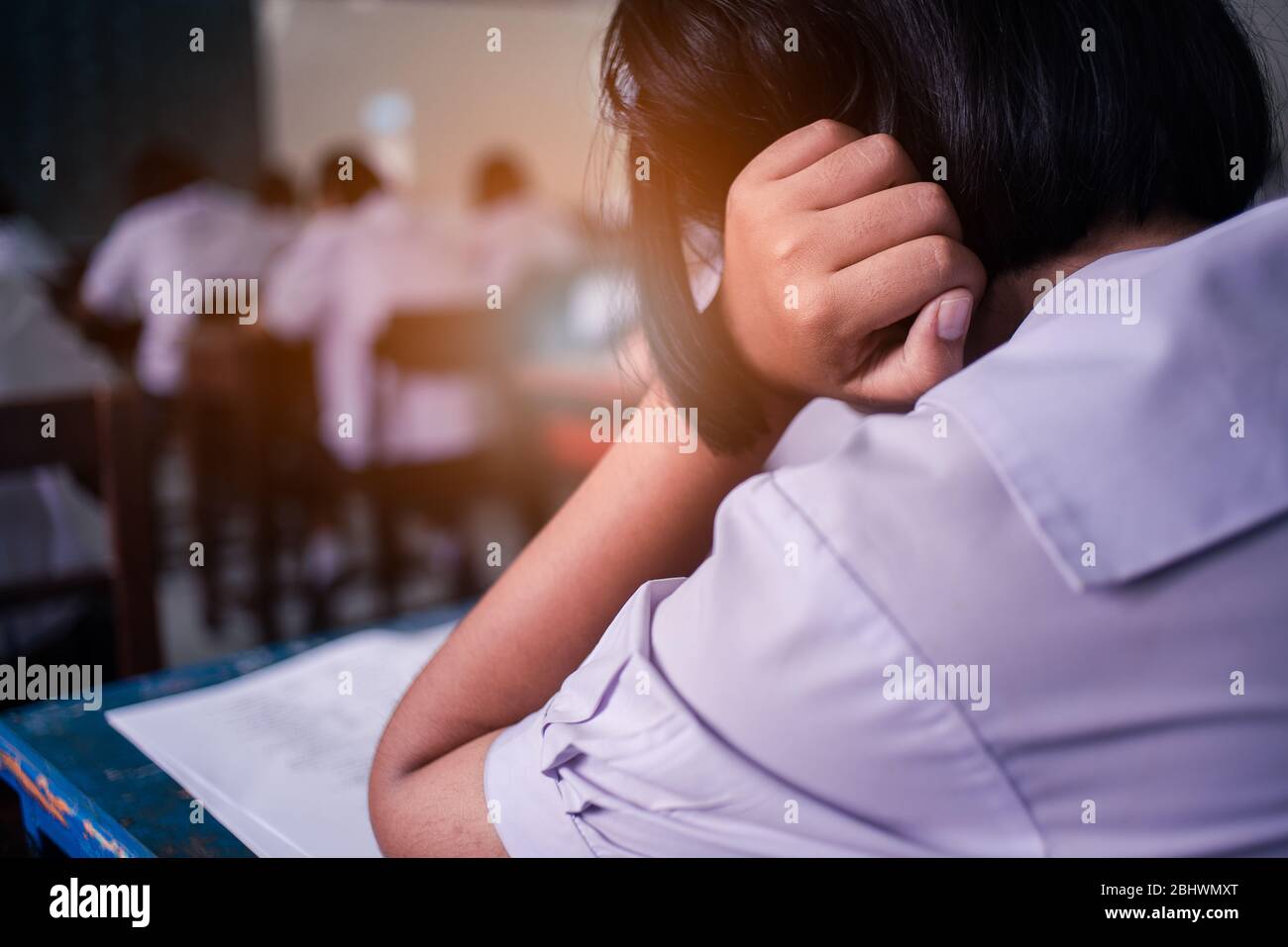 School students thinking and taking exam answer in classroom with ...