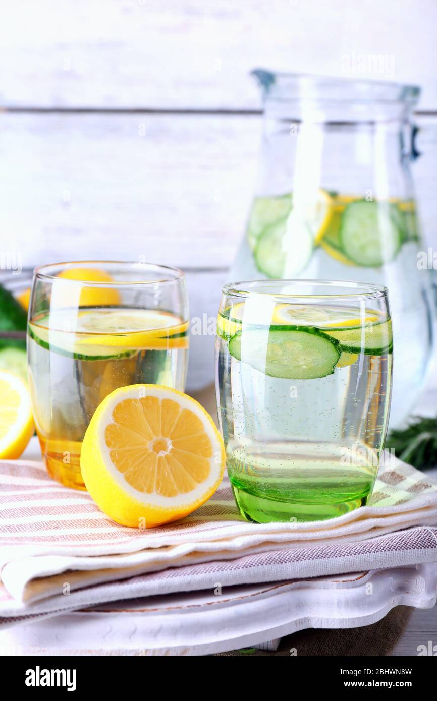 Fresh water with lemon and cucumber in glassware on wooden background ...