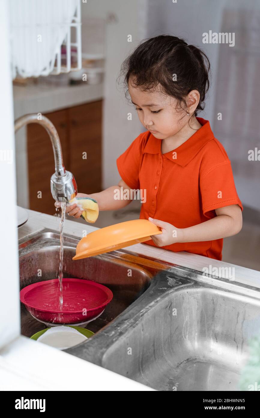 kid washing the dishes. helpful young girl doing clean up at home Stock ...