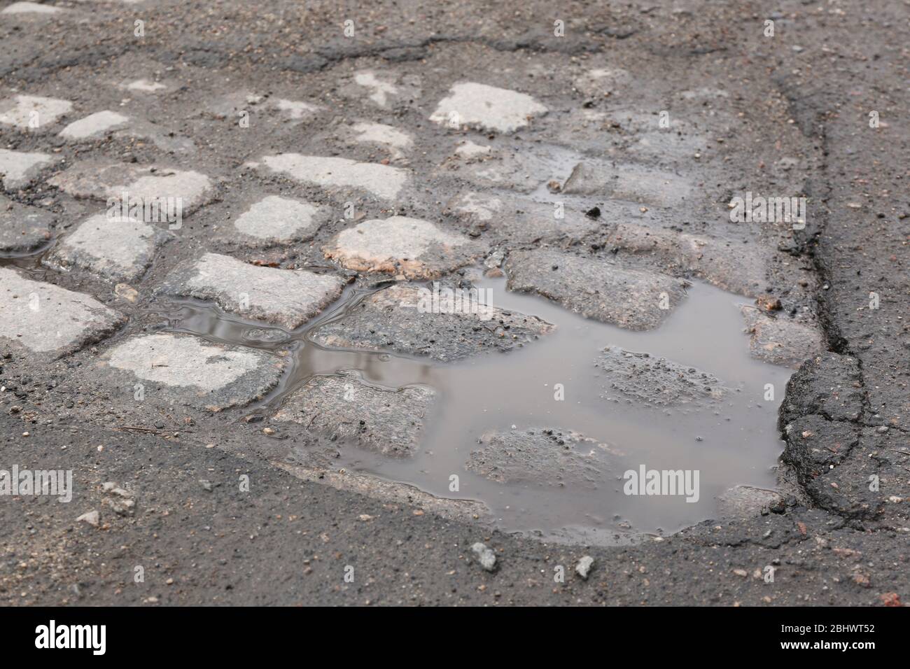 Very bad quality road with potholes and puddles Stock Photo - Alamy