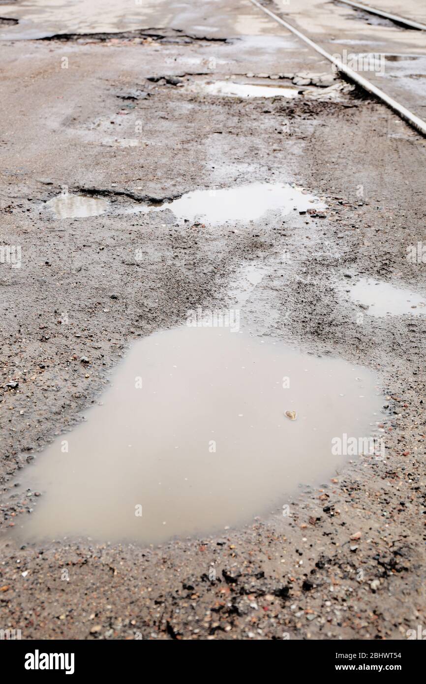 Very bad quality road with potholes and puddles Stock Photo - Alamy