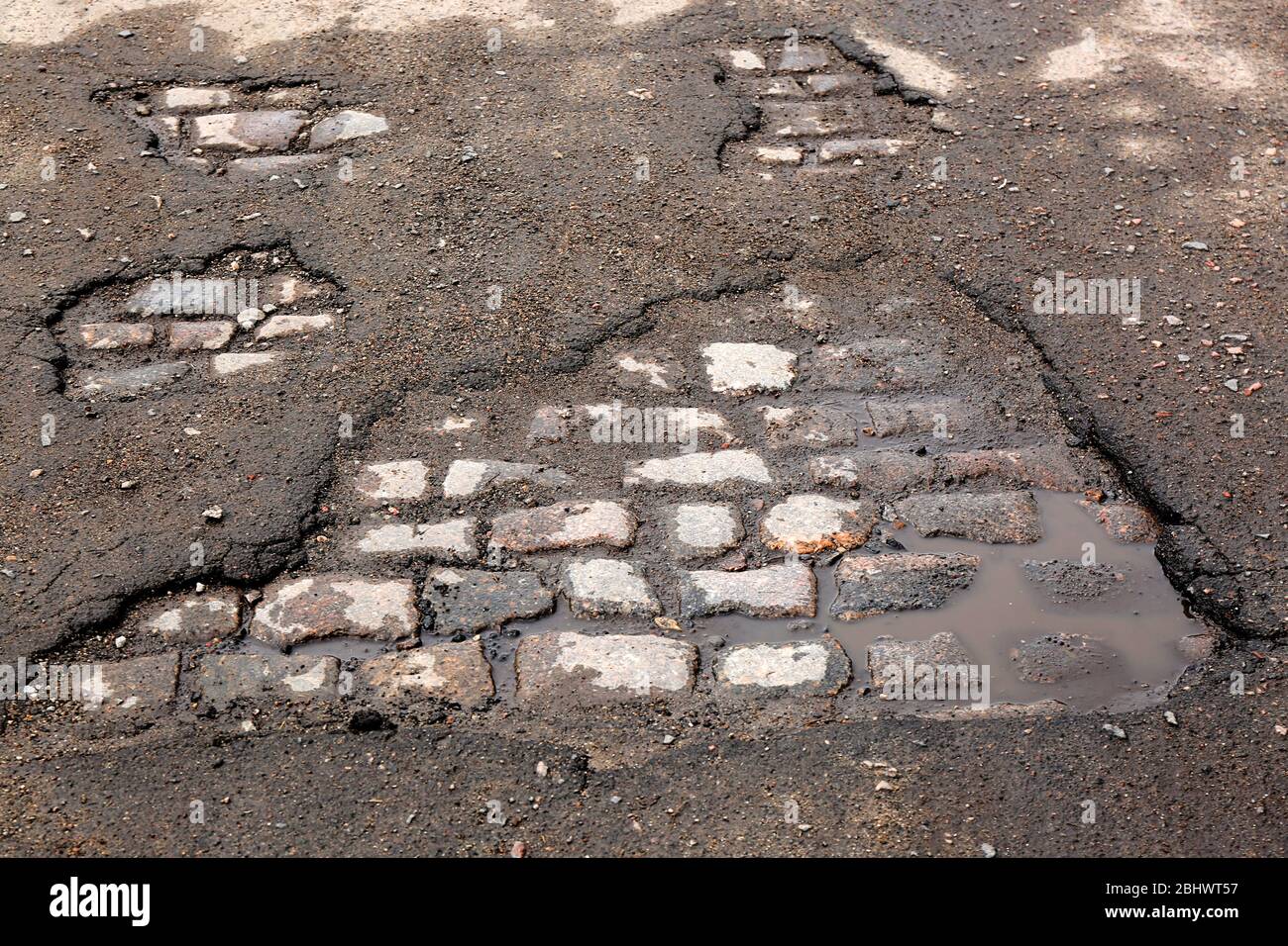 Very bad quality road with potholes and puddles Stock Photo - Alamy