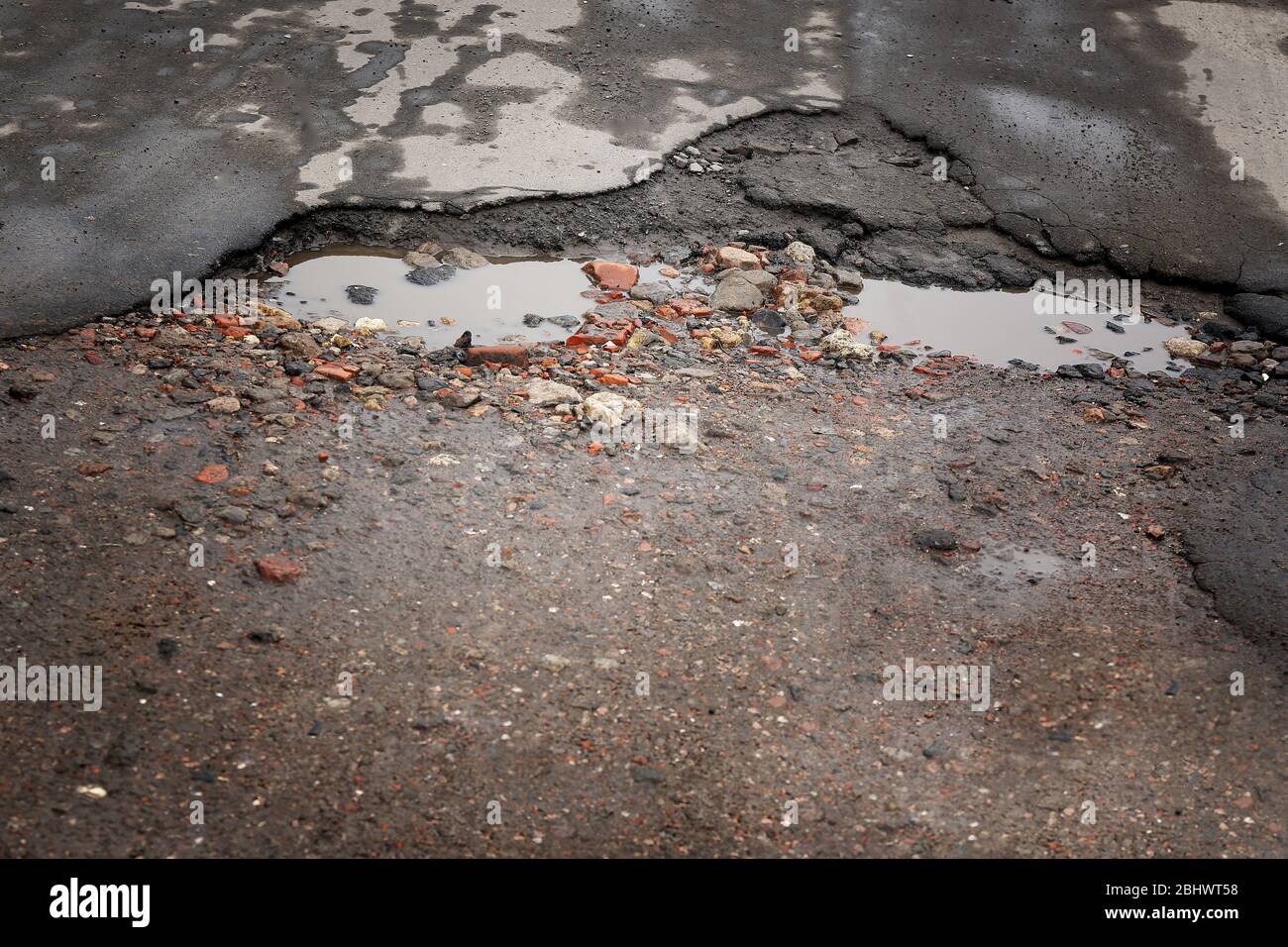 Very bad quality road with potholes and puddles Stock Photo - Alamy