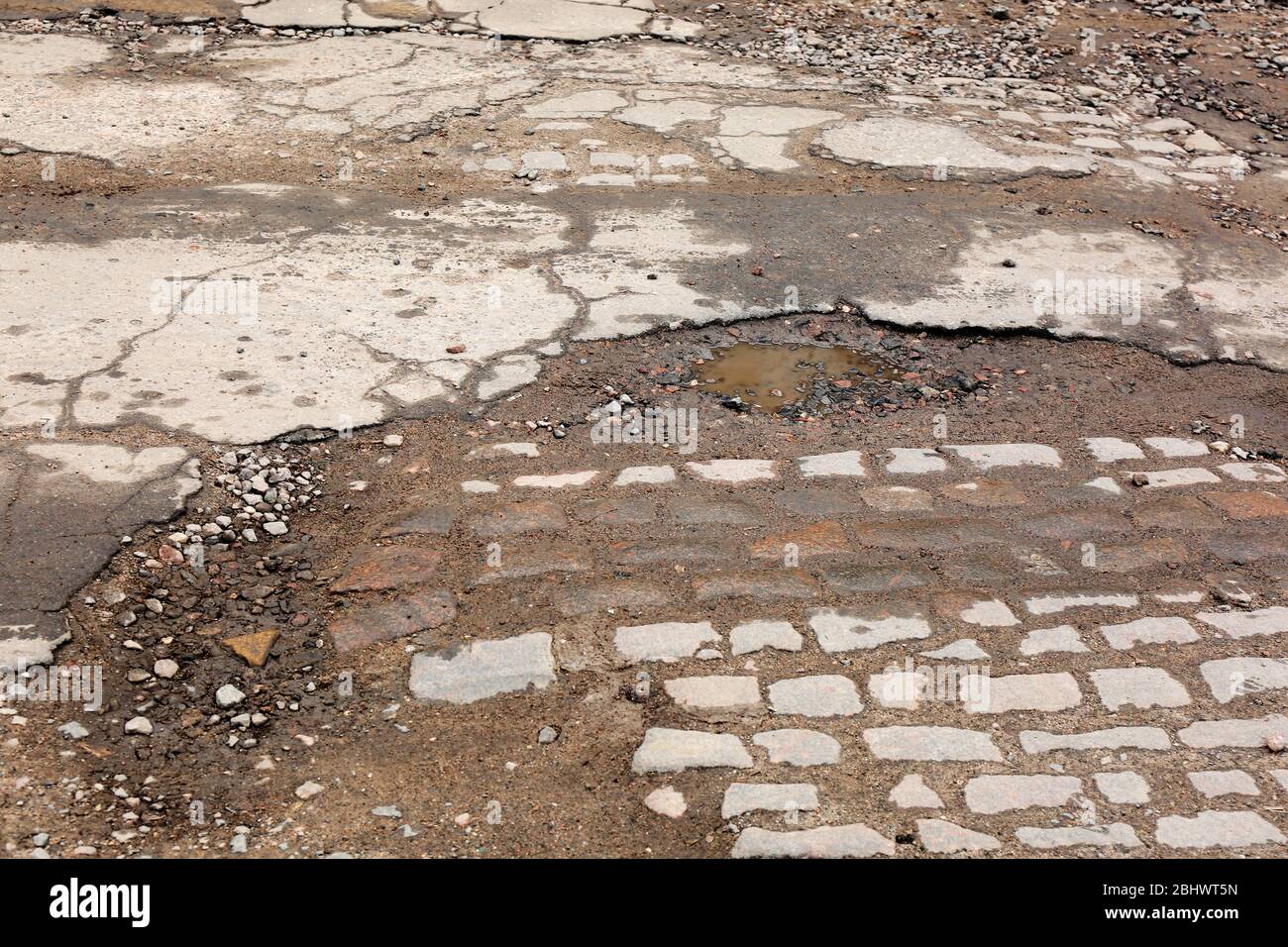Very bad quality road with potholes and puddles Stock Photo - Alamy