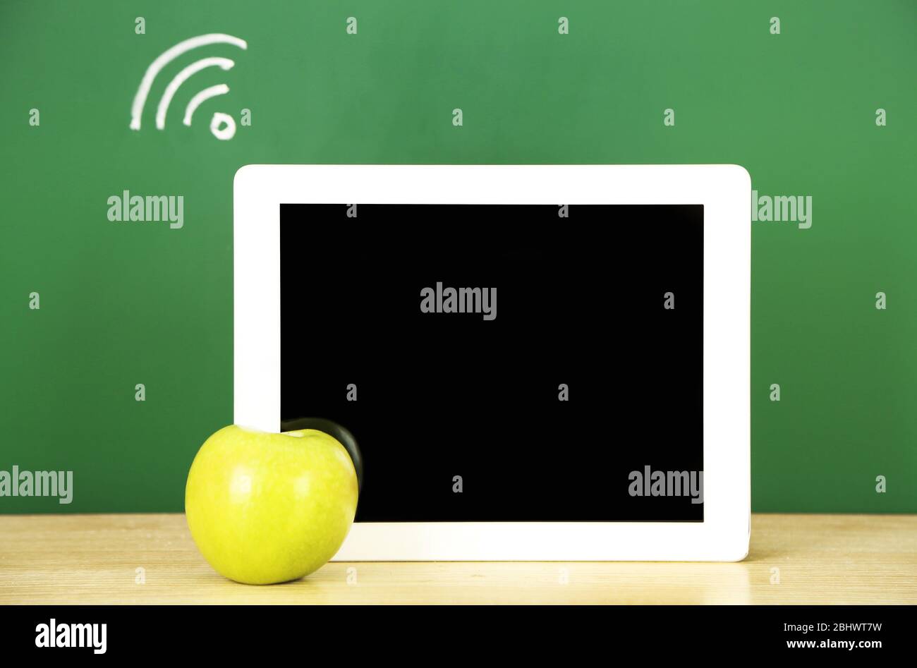 Tablet on table, on green blackboard background Stock Photo - Alamy