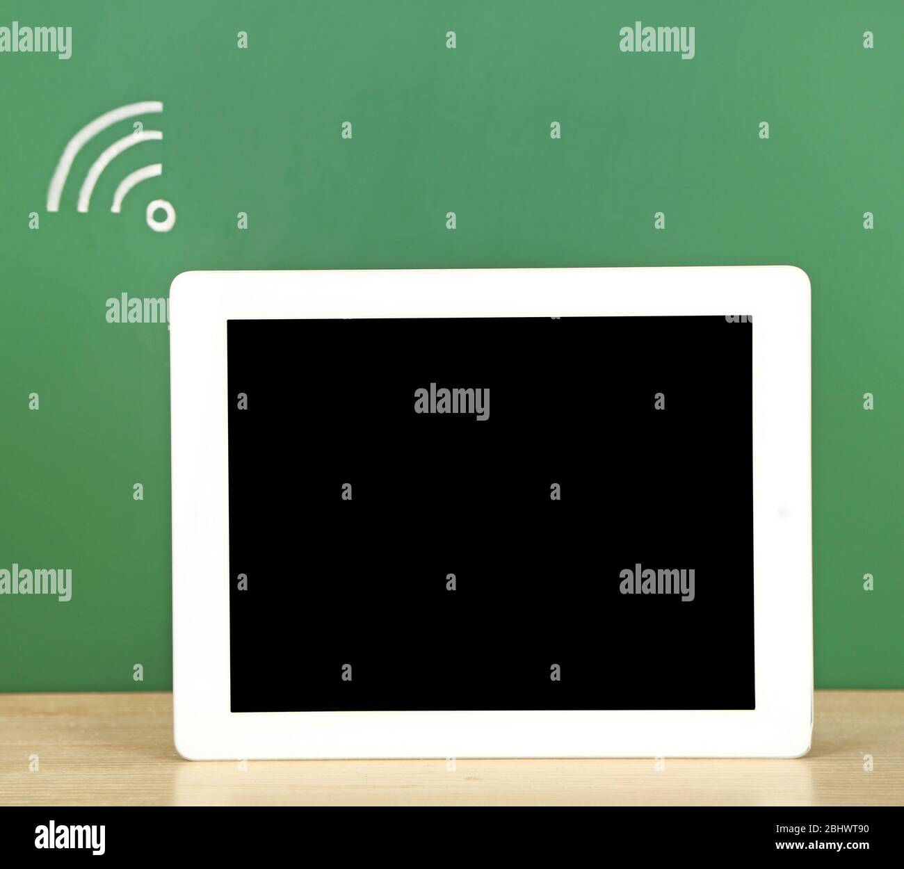 Tablet on table, on green blackboard background Stock Photo - Alamy