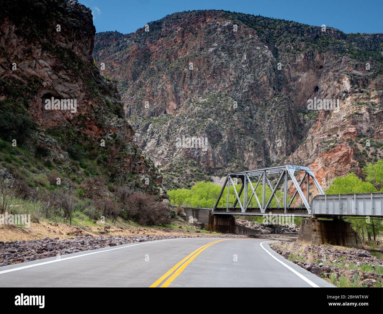 Railroad bridge over roadway and towering cliffs in Rainbow Canyon ...