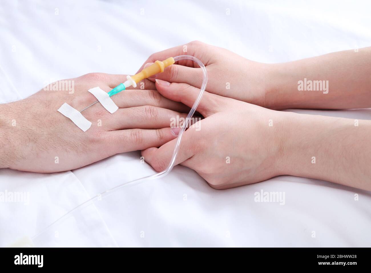 Female hands holding man hand with dropper needle on bed close-up Stock ...