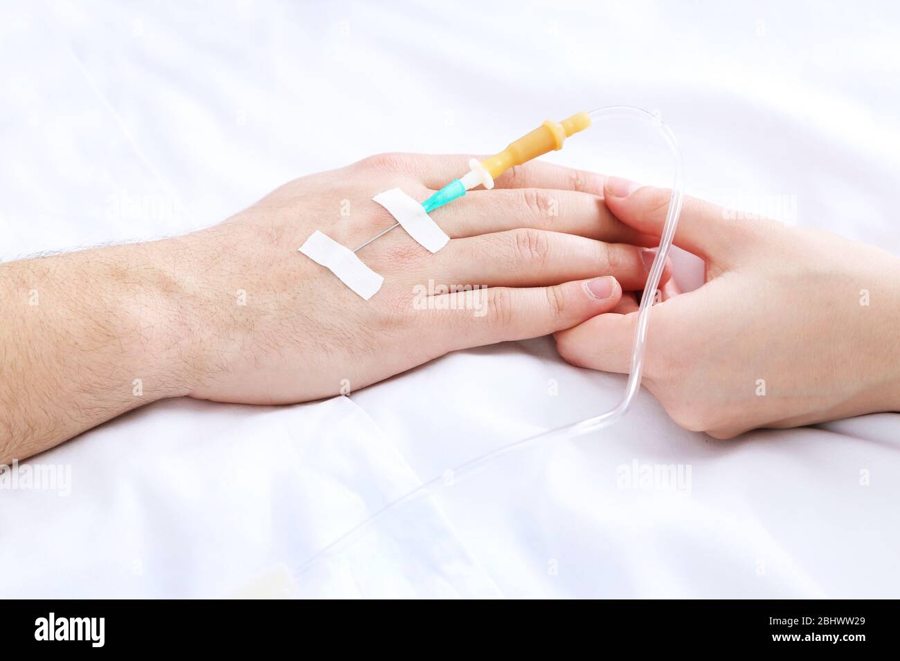 Female hand holding man hand with dropper needle on bed close-up Stock ...