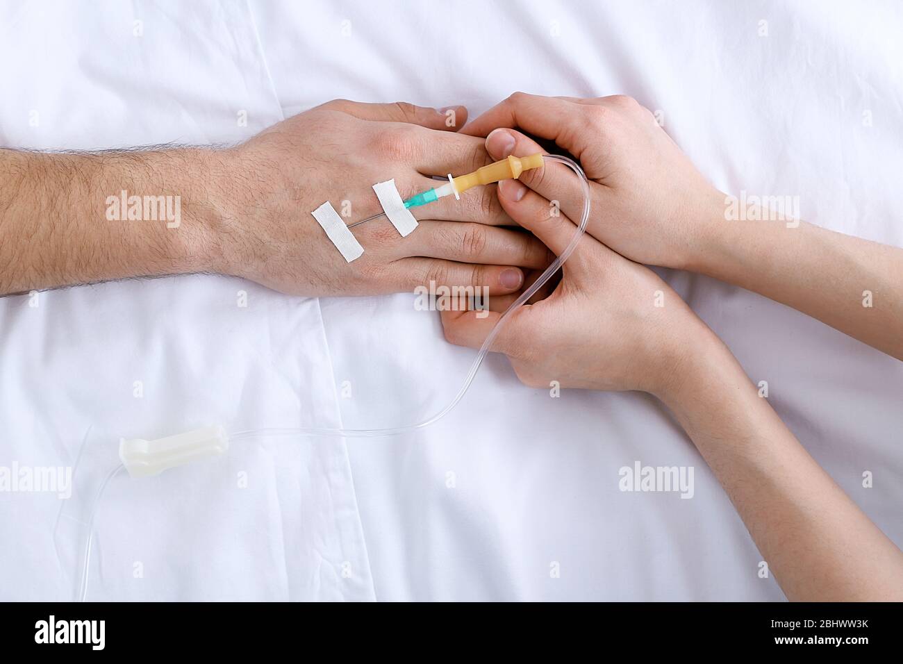 Female hands holding man hand with dropper needle on bed close-up Stock ...