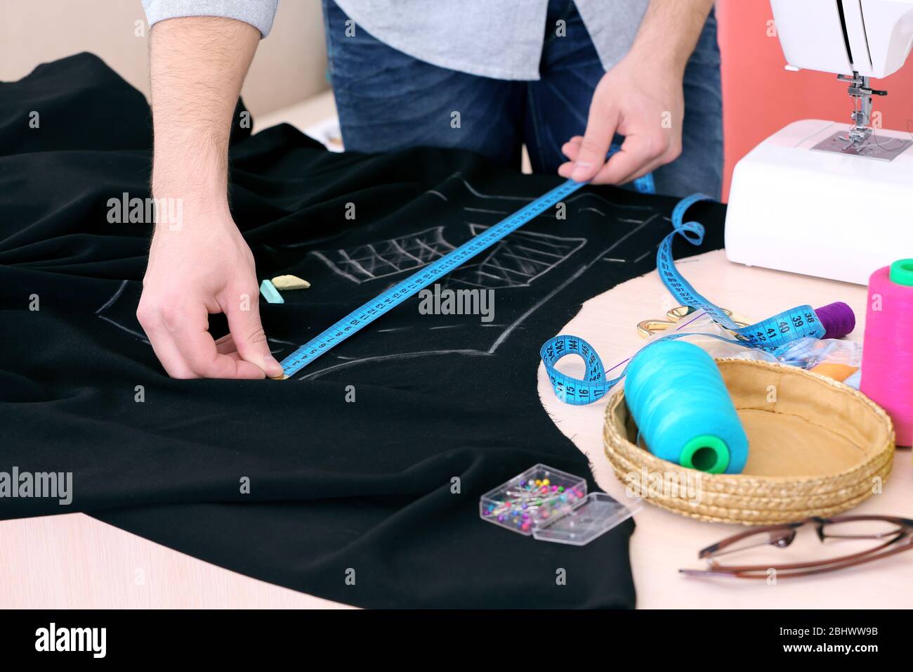 Male dressmaker drawing line on fabric on table close-up Stock Photo ...