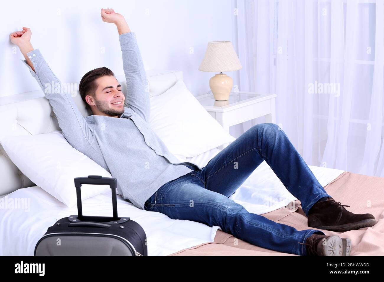Tired man resting on bed in room Stock Photo - Alamy