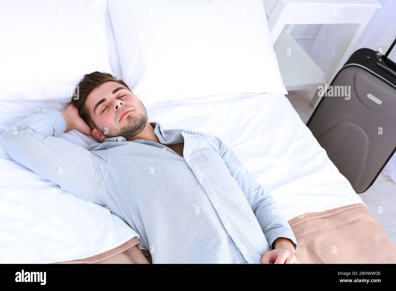 Tired man resting on bed in room Stock Photo - Alamy