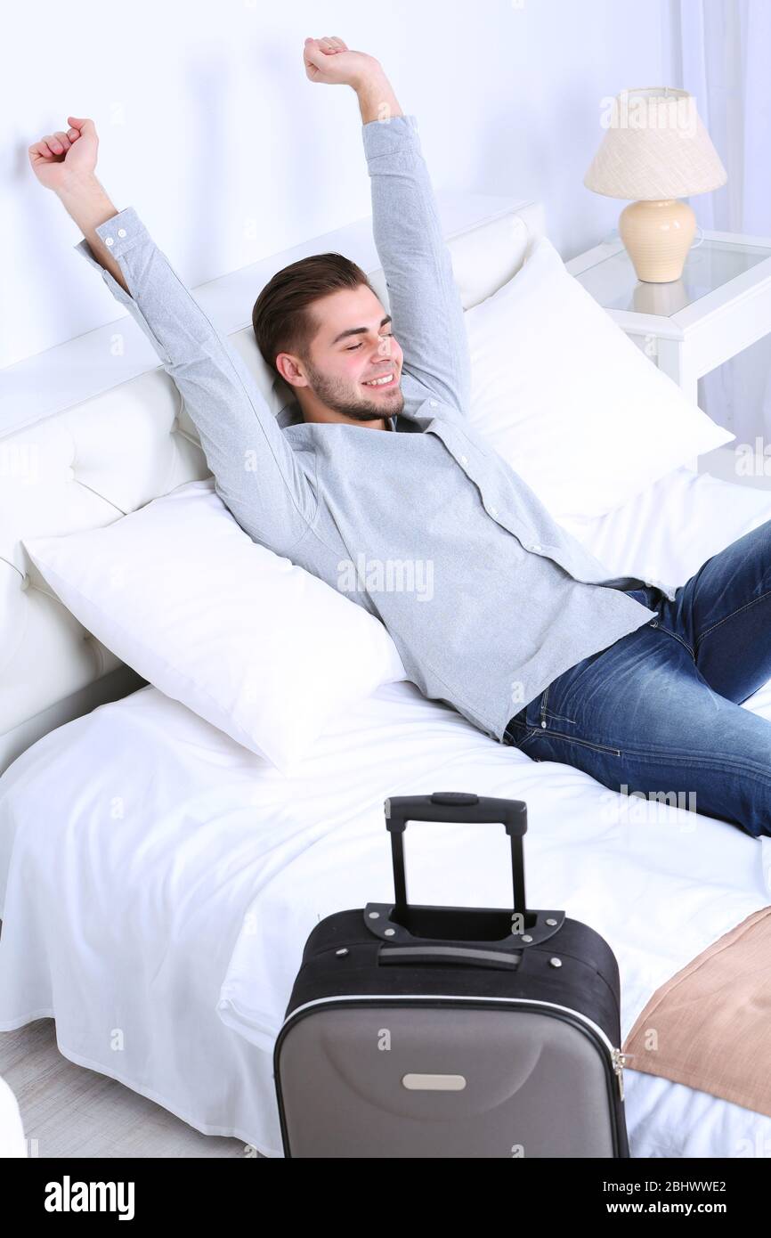 Tired man resting on bed in room Stock Photo - Alamy