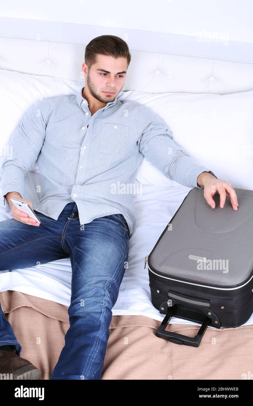 Tired man resting on bed in room Stock Photo - Alamy