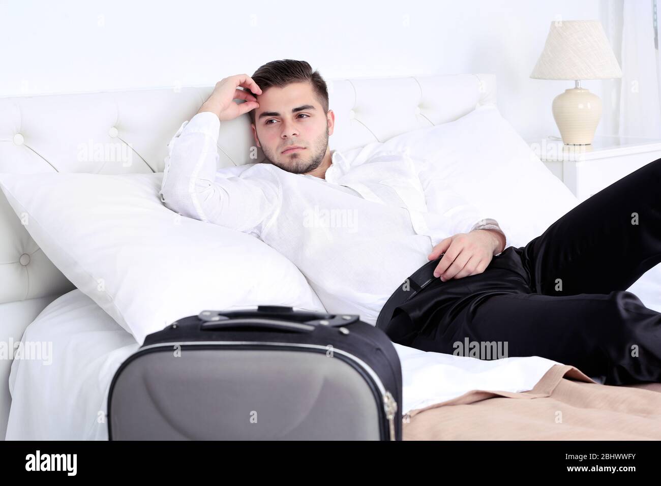 Tired man resting on bed in room Stock Photo - Alamy