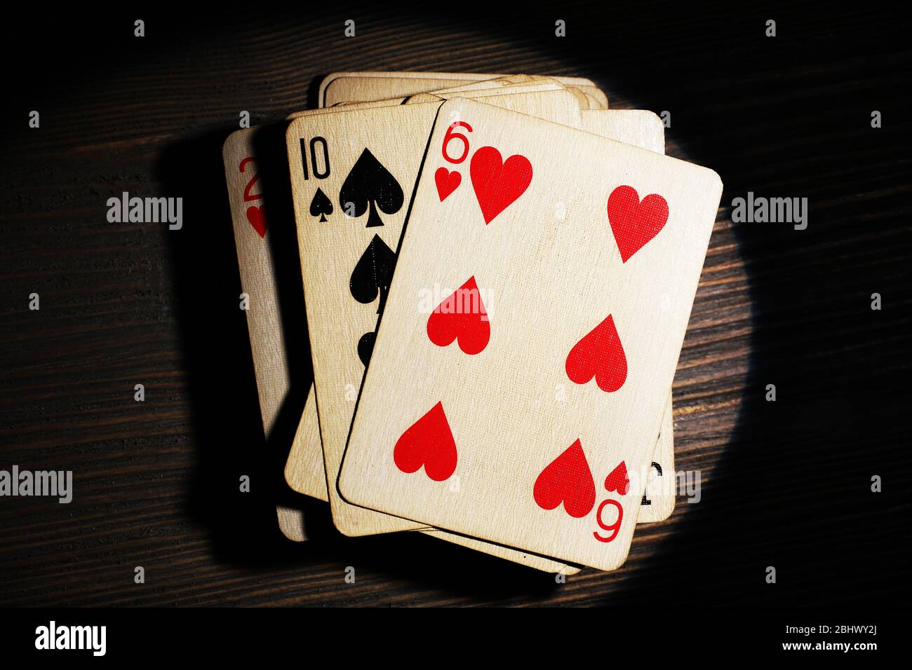 Stack of playing cards in light on wooden table, top view Stock Photo ...