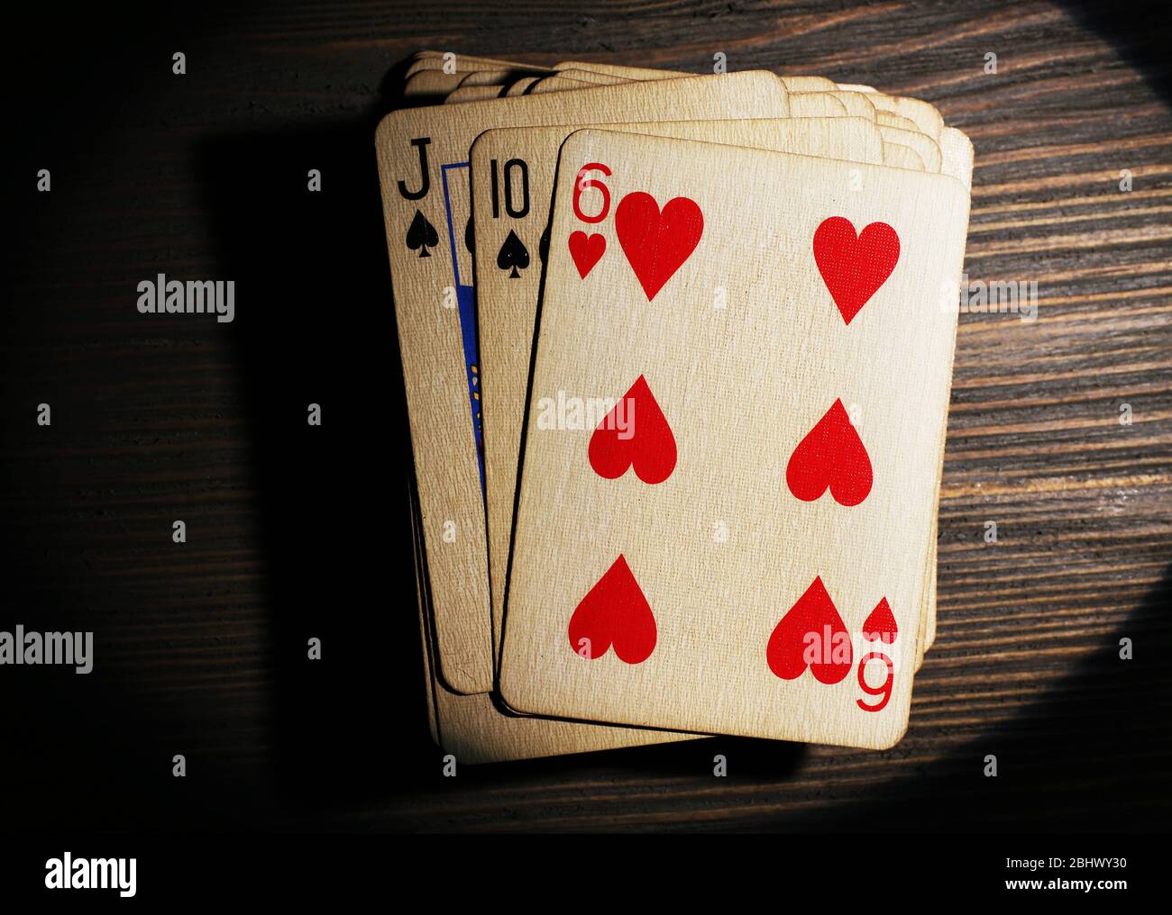 Stack of playing cards in light on wooden table, top view Stock Photo ...
