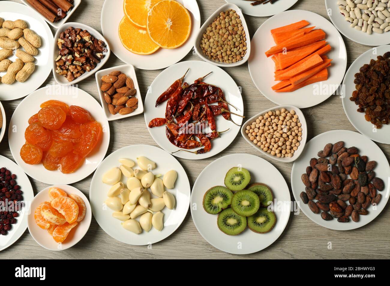 Different products on saucers on wooden table, top view Stock Photo - Alamy